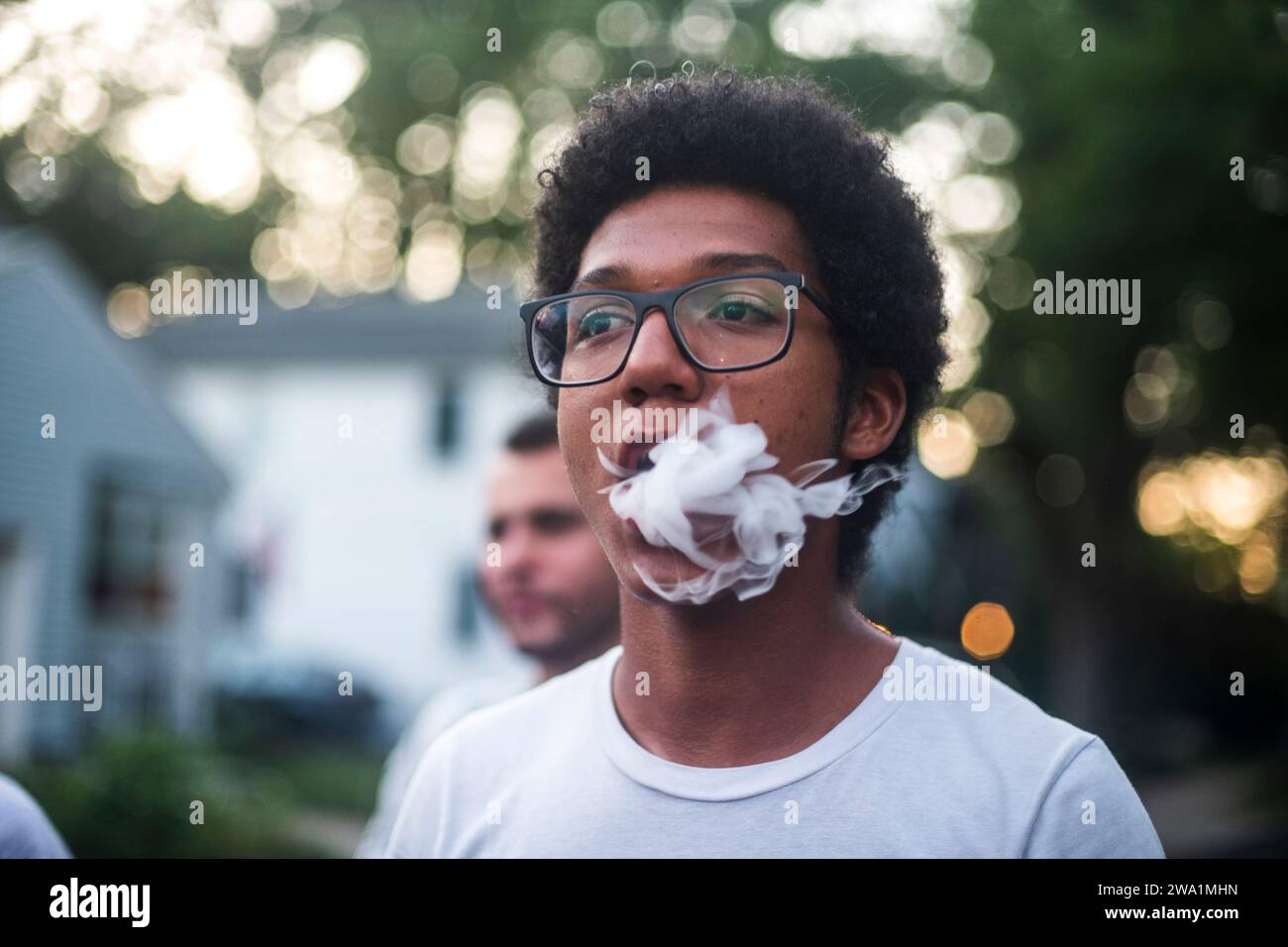Young man vaping and exhaling smoke Stock Photo - Alamy