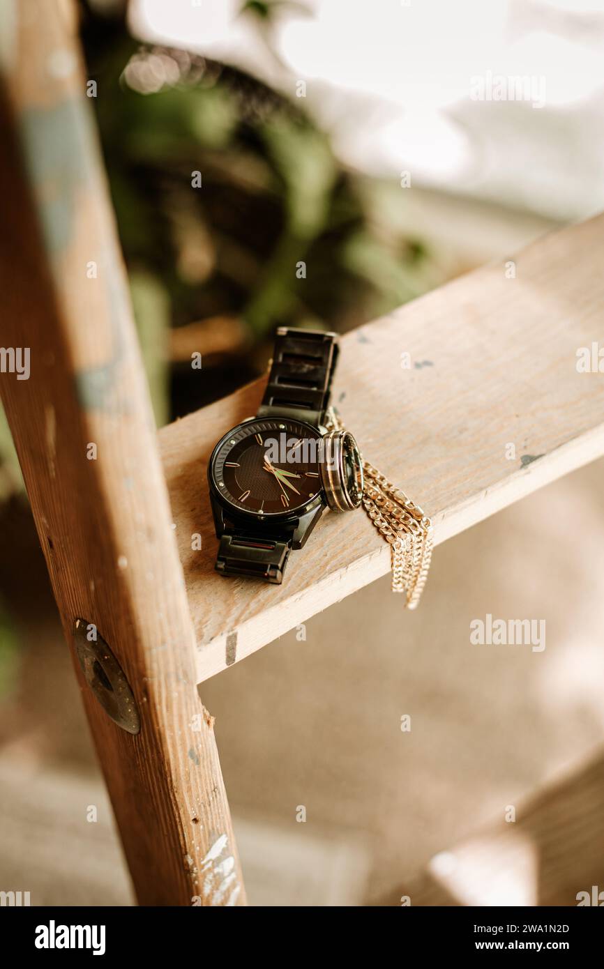 Men's black watch on a wooden ladder with wedding ring Stock Photo - Alamy