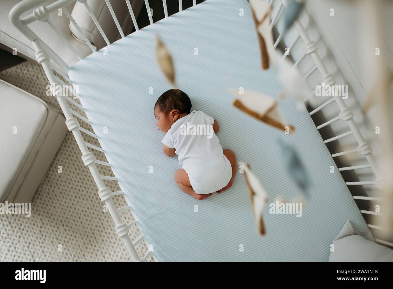 Overhead look at a newborn baby in his crib with a mobile in view Stock ...