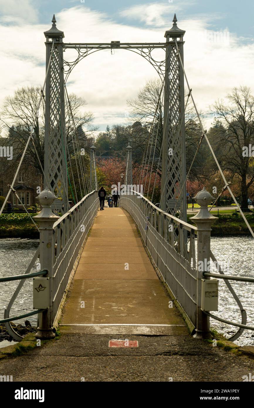 Pedestrians cross one of the historic suspension bridges which cross ...