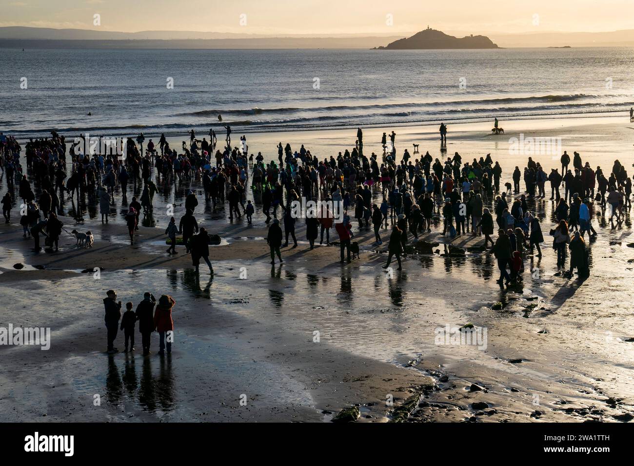 People gather on the beach to watch the Loony Dook New Year's Day dip ...