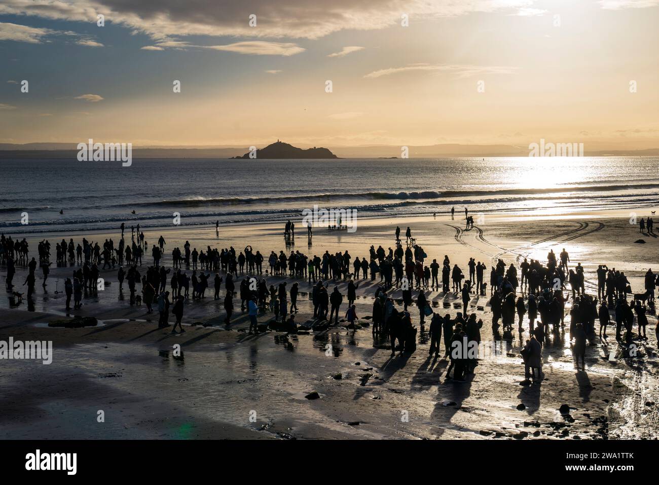 People gather on the beach to watch the Loony Dook New Year's Day dip ...