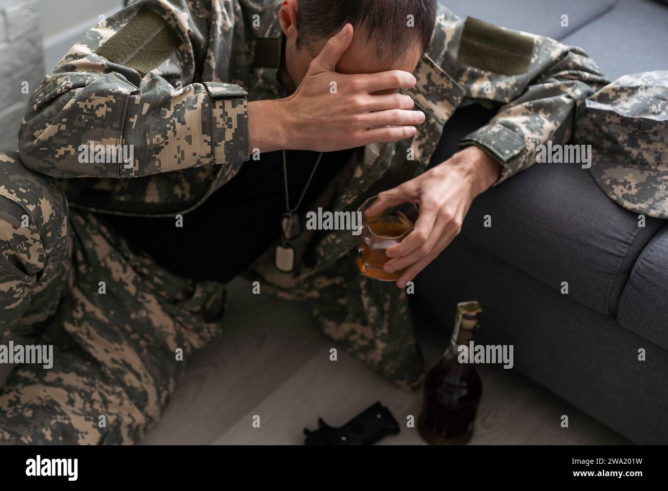 Upset male soldier drinking bottled alcoholic beverage at home and ...