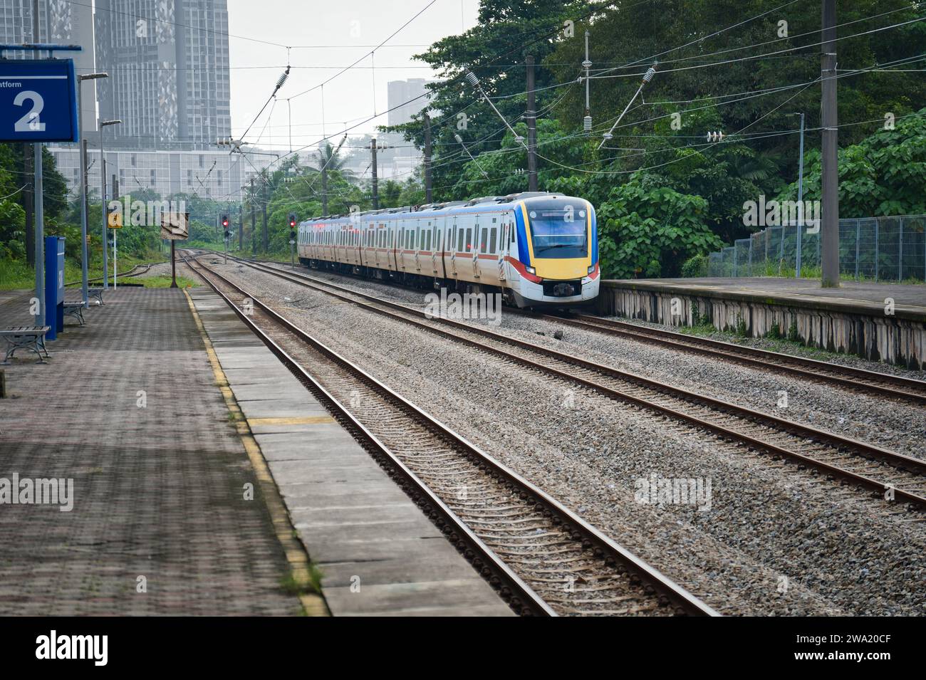 Commuter train arriving at a platform on a gravel railway track, with ...