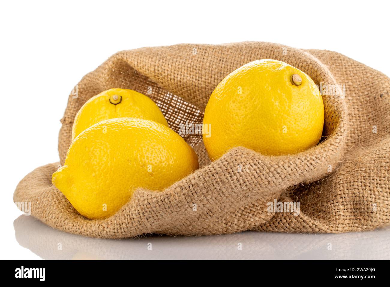 Three bright yellow organic lemons in a jute bag, macro, isolated on ...