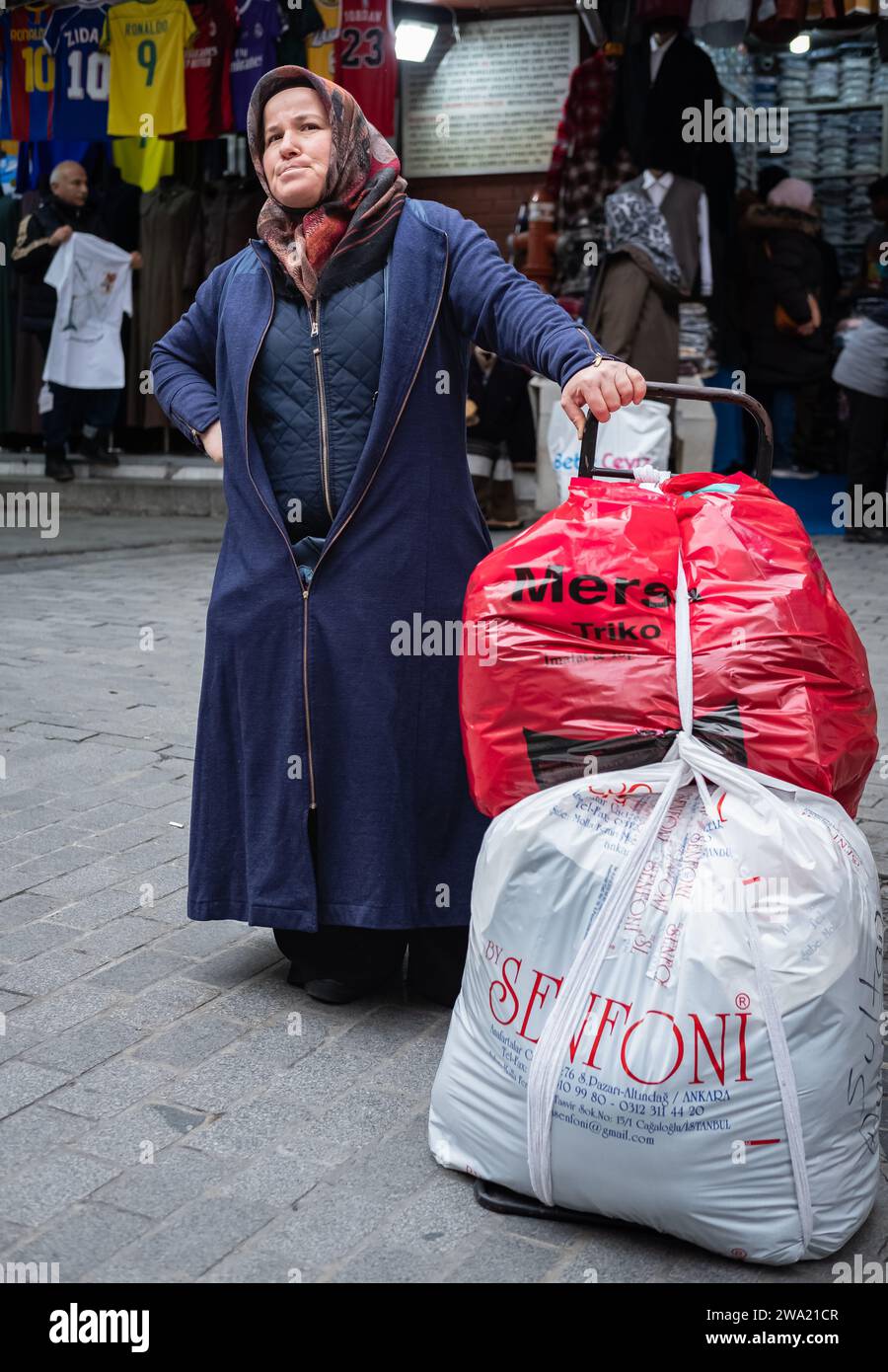 Mid age woman carrying a heavy luggage with difficulty on a street road ...