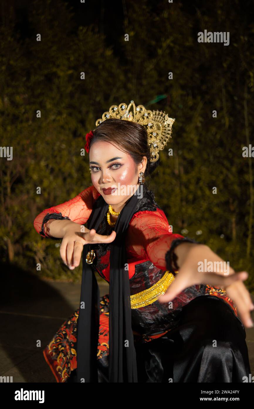 An Asian dancer in a red costume poses very flexibly on a stage at ...