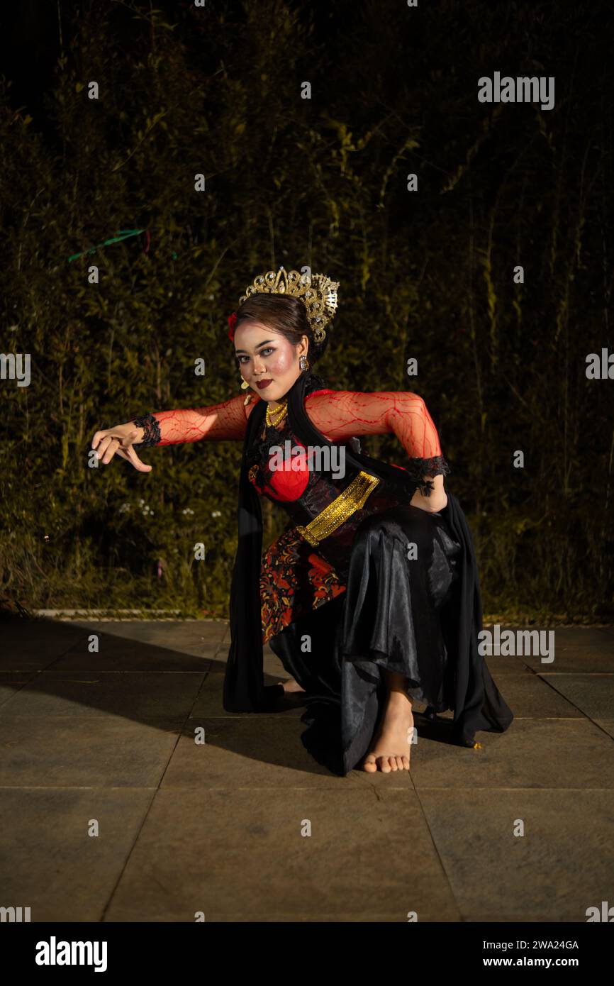 An Asian dancer in a red costume poses very flexibly on a stage at ...
