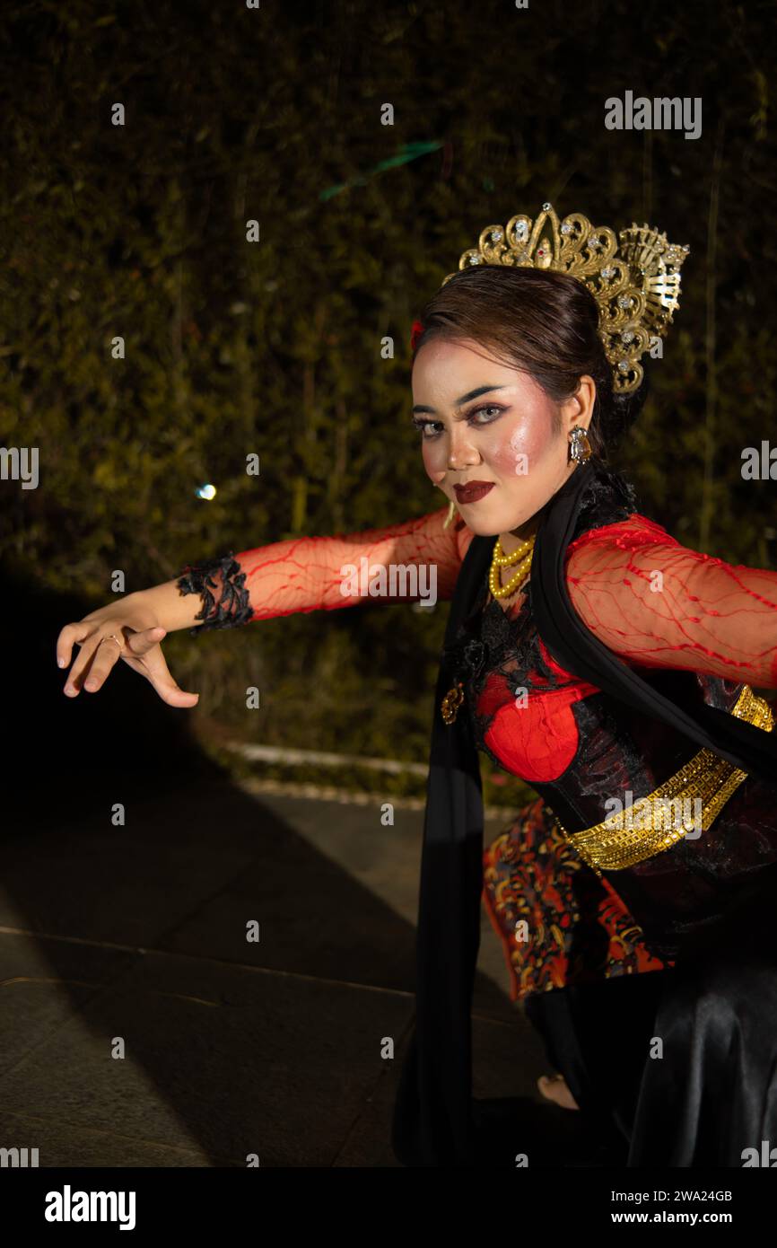 An Asian dancer in a red costume poses very flexibly on a stage at ...