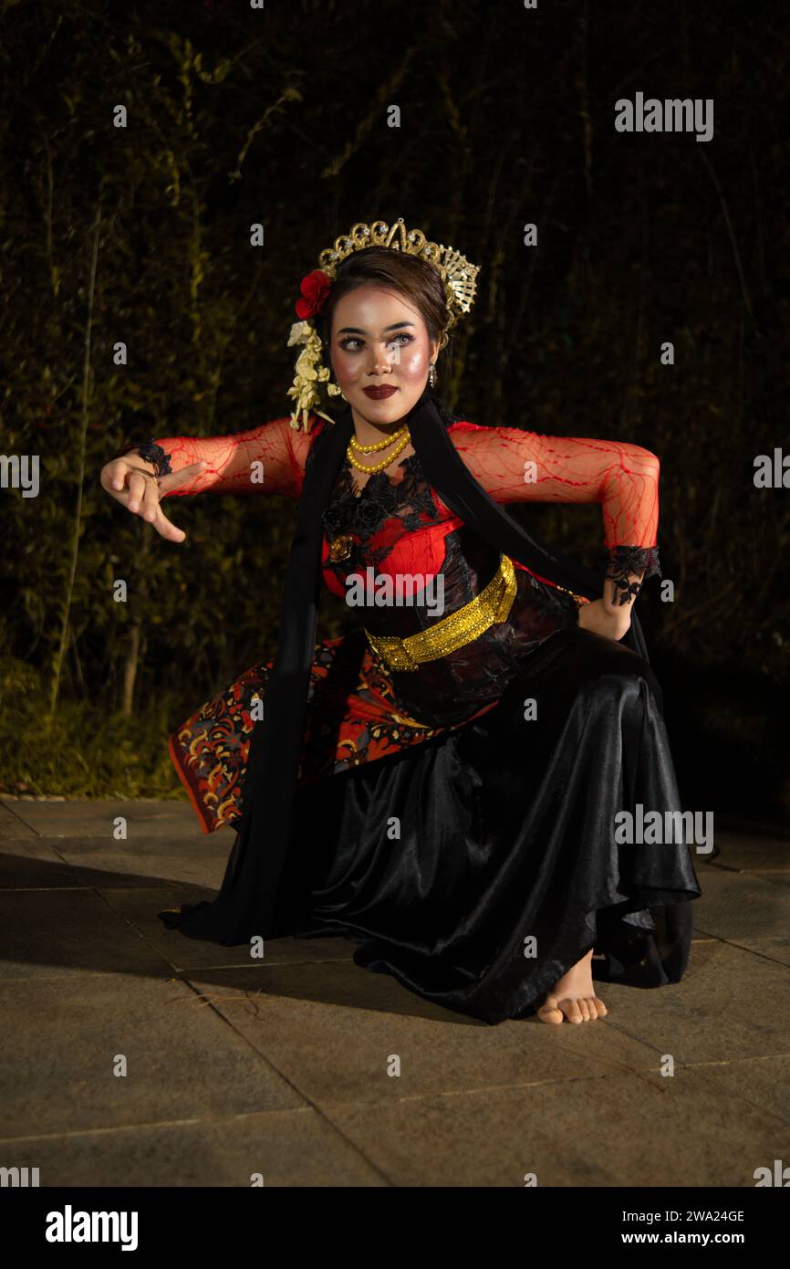 An Asian dancer in a red costume poses very flexibly on a stage at ...