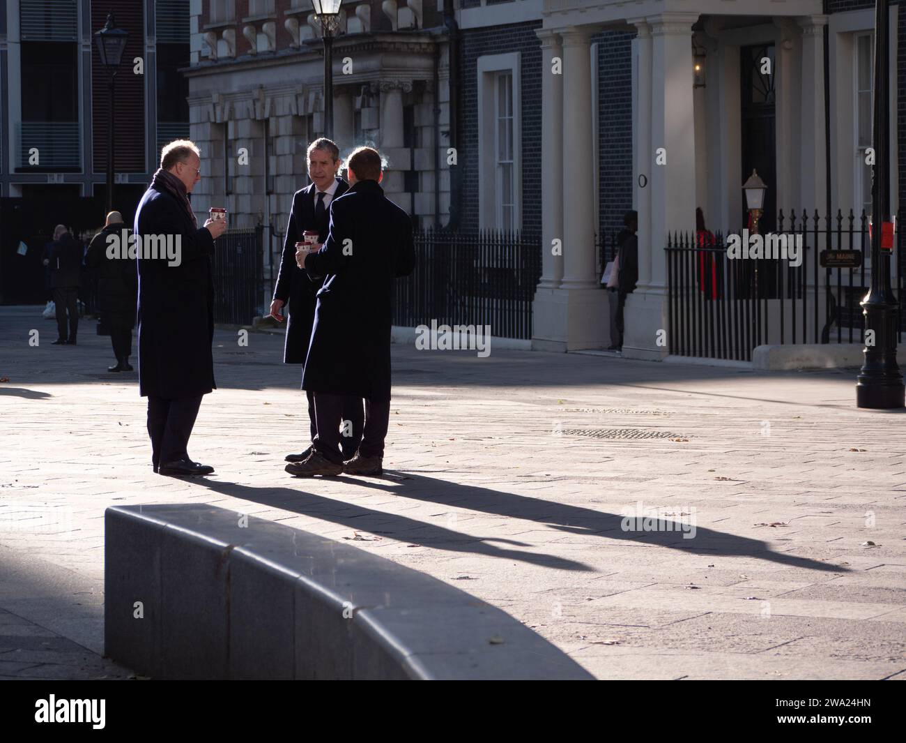 London, UK. City workers wearing suits talking outside offices drinking ...