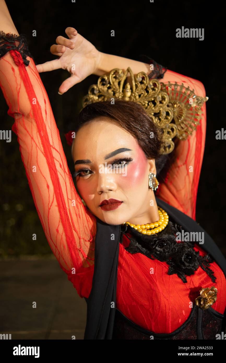 a Balinese woman wears heavy makeup with rosy red lips and sharp hair ...