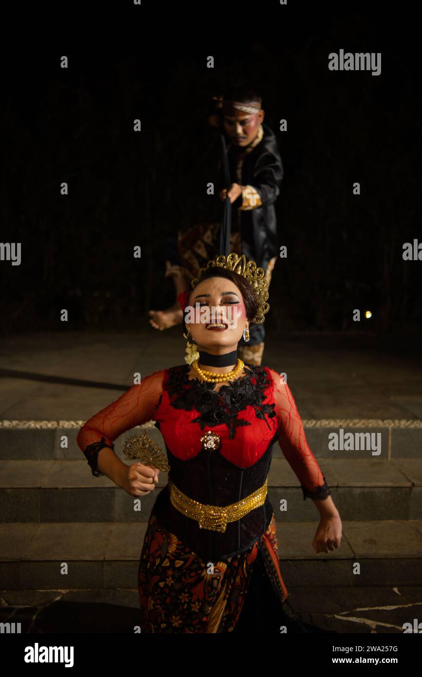 female dancers tied by black scarves while being held by men with sad ...
