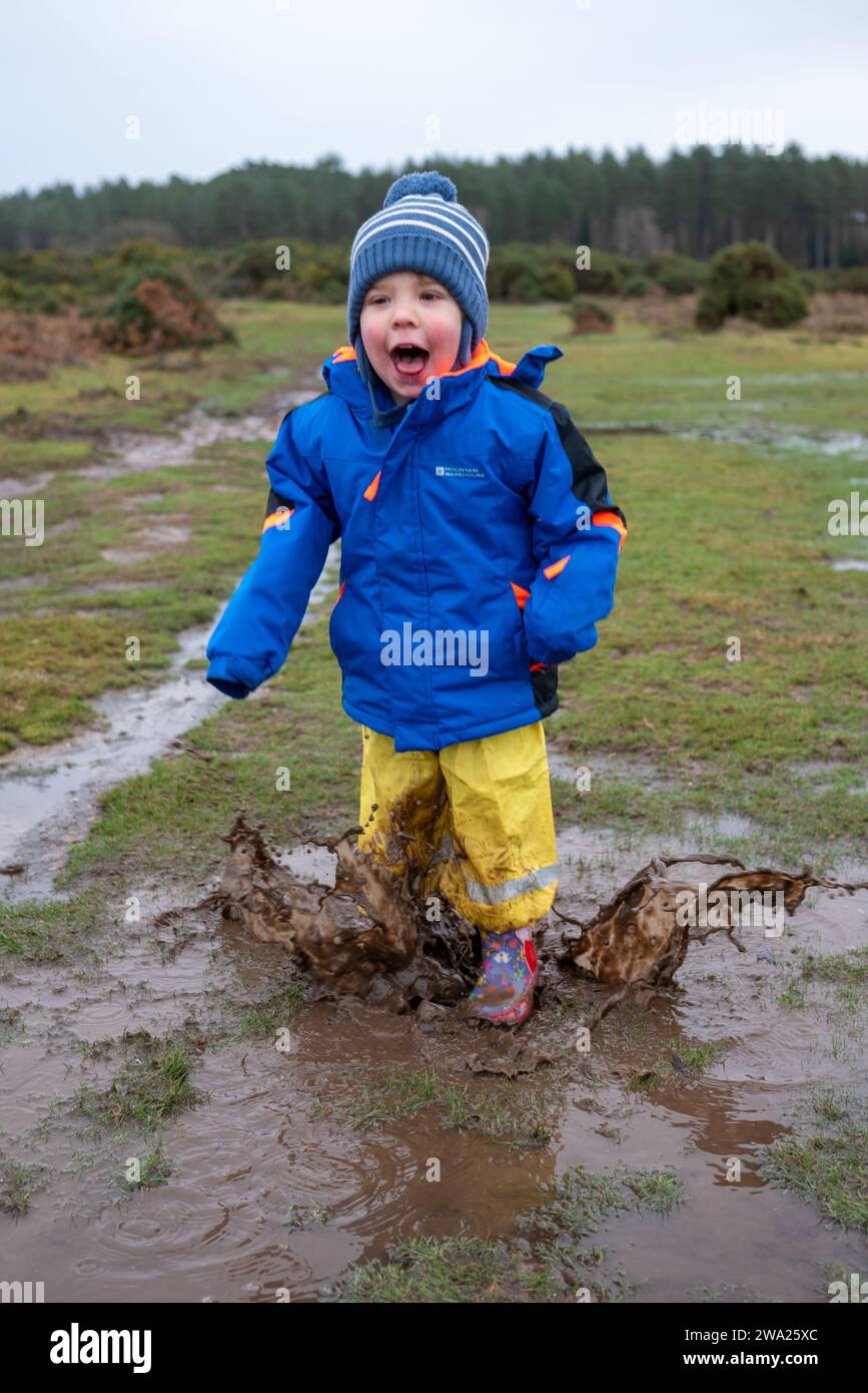 Two year old boy jumping in a puddle, splashing in a puddle, making a ...
