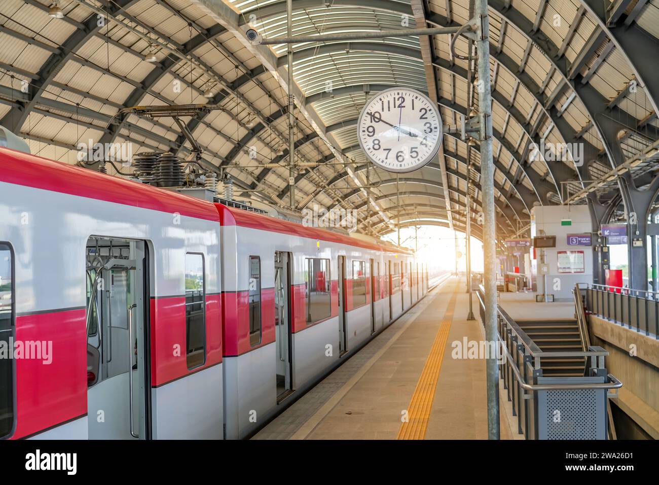 Clock on a pole on the passenger platform at a train station awaiting ...