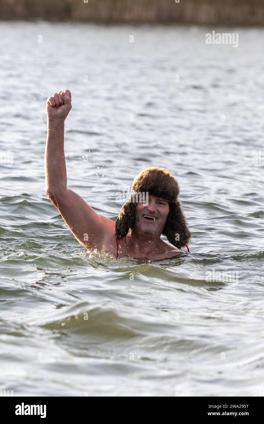 Luppa, Germany. 01st Jan, 2024. A man raises his arm in the water. A ...