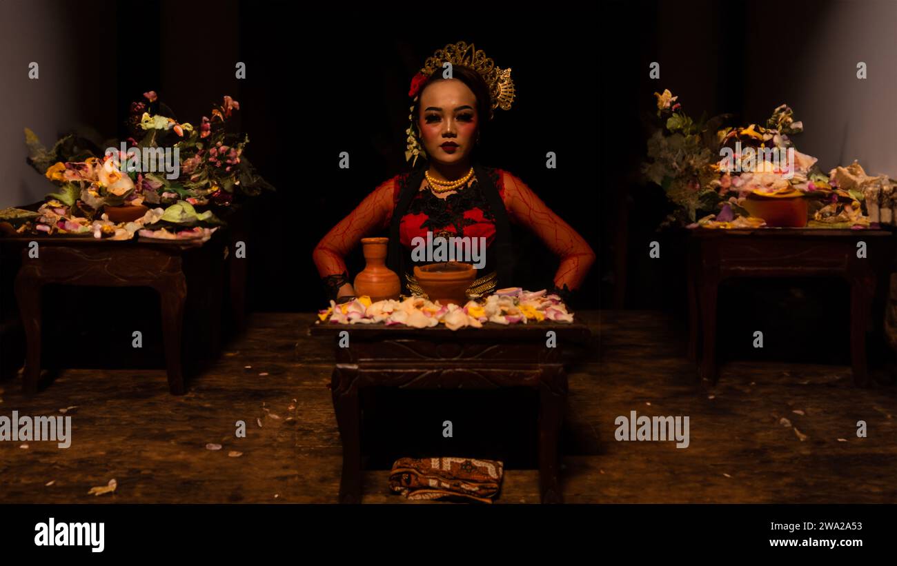 a female dancer sits gracefully and begins her ritual in front of ...
