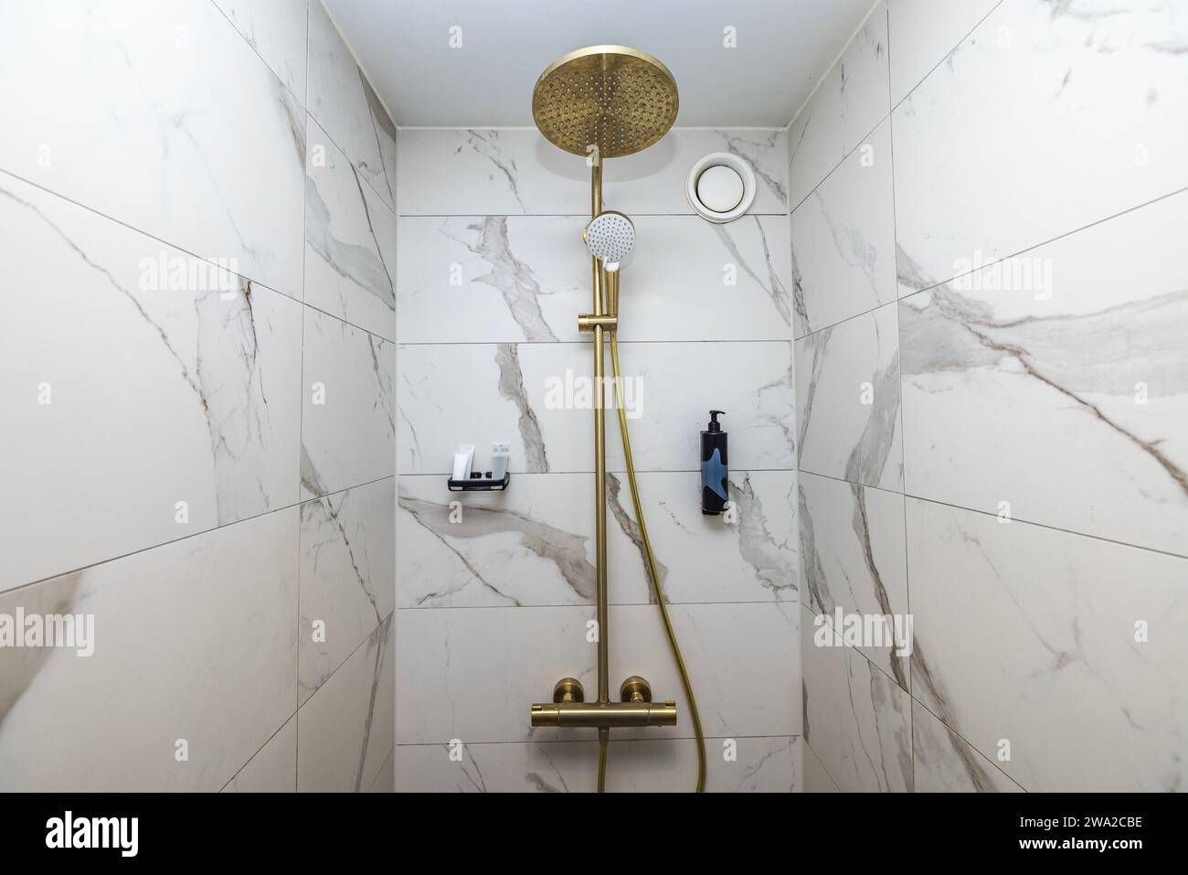 Close-up view of the hotel shower room with tiled walls and a shower ...