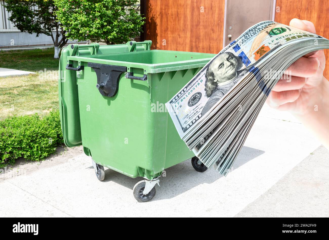 Opened big green plastic garbage container and stack of american ...