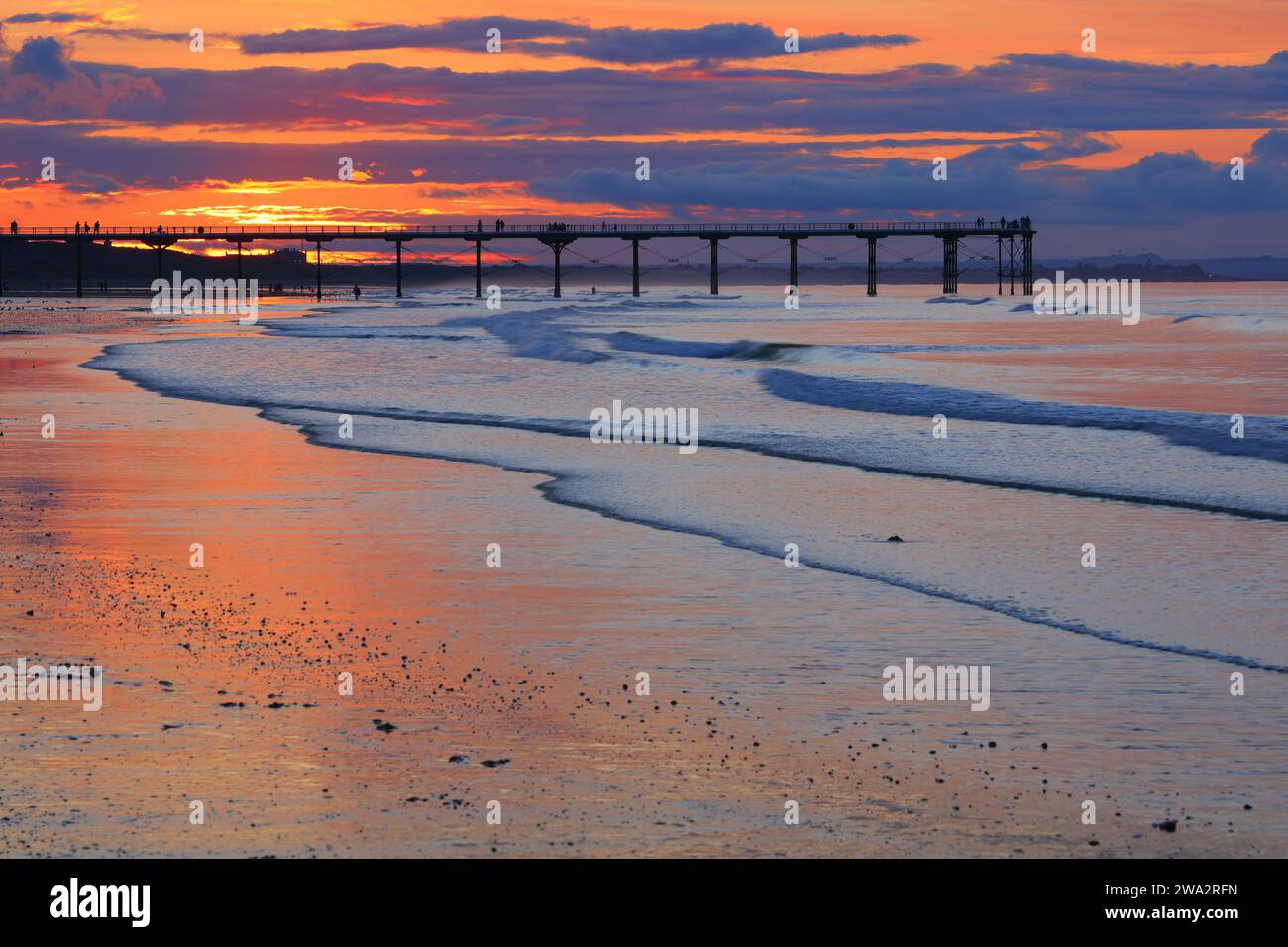 Beautiful light reflecting of a beach with a pier in the background ...