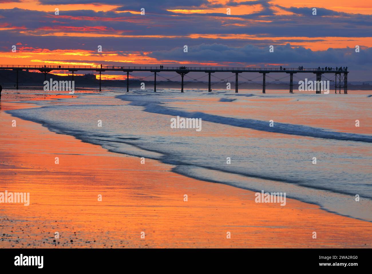 Beautiful light reflecting of a beach with a pier in the background ...