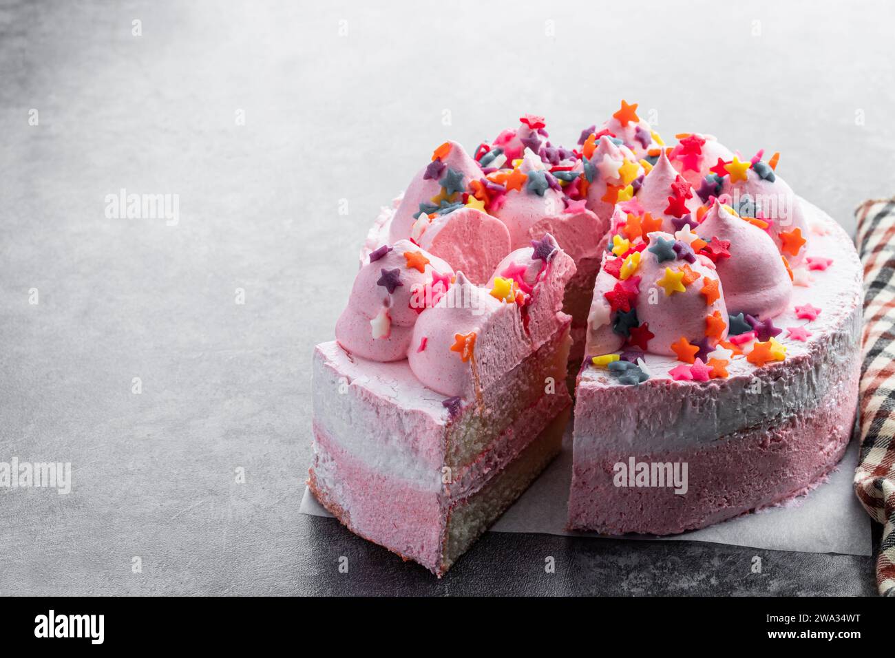 Pink Sponge cake decorated with small meringue on top on gray ...