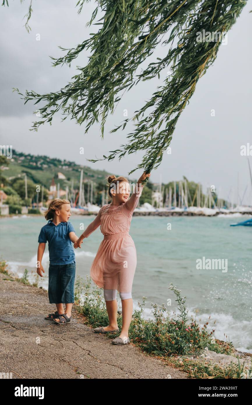 Sweet little kids playing by the lake on a very windy day under summer ...