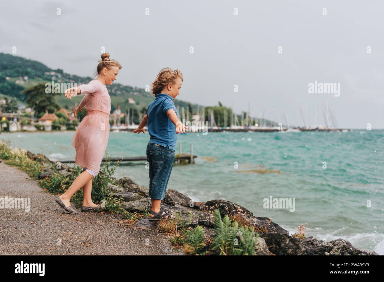 Sweet little kids playing by the lake on a very windy day under summer ...