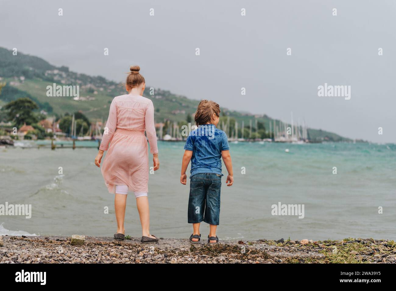 Sweet little kids playing by the lake on a very windy day under summer ...