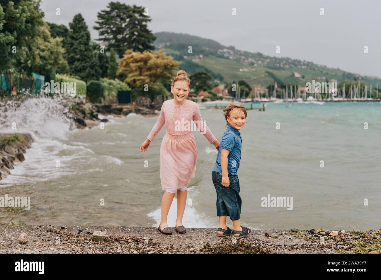 Sweet little kids playing by the lake on a very windy day under summer ...
