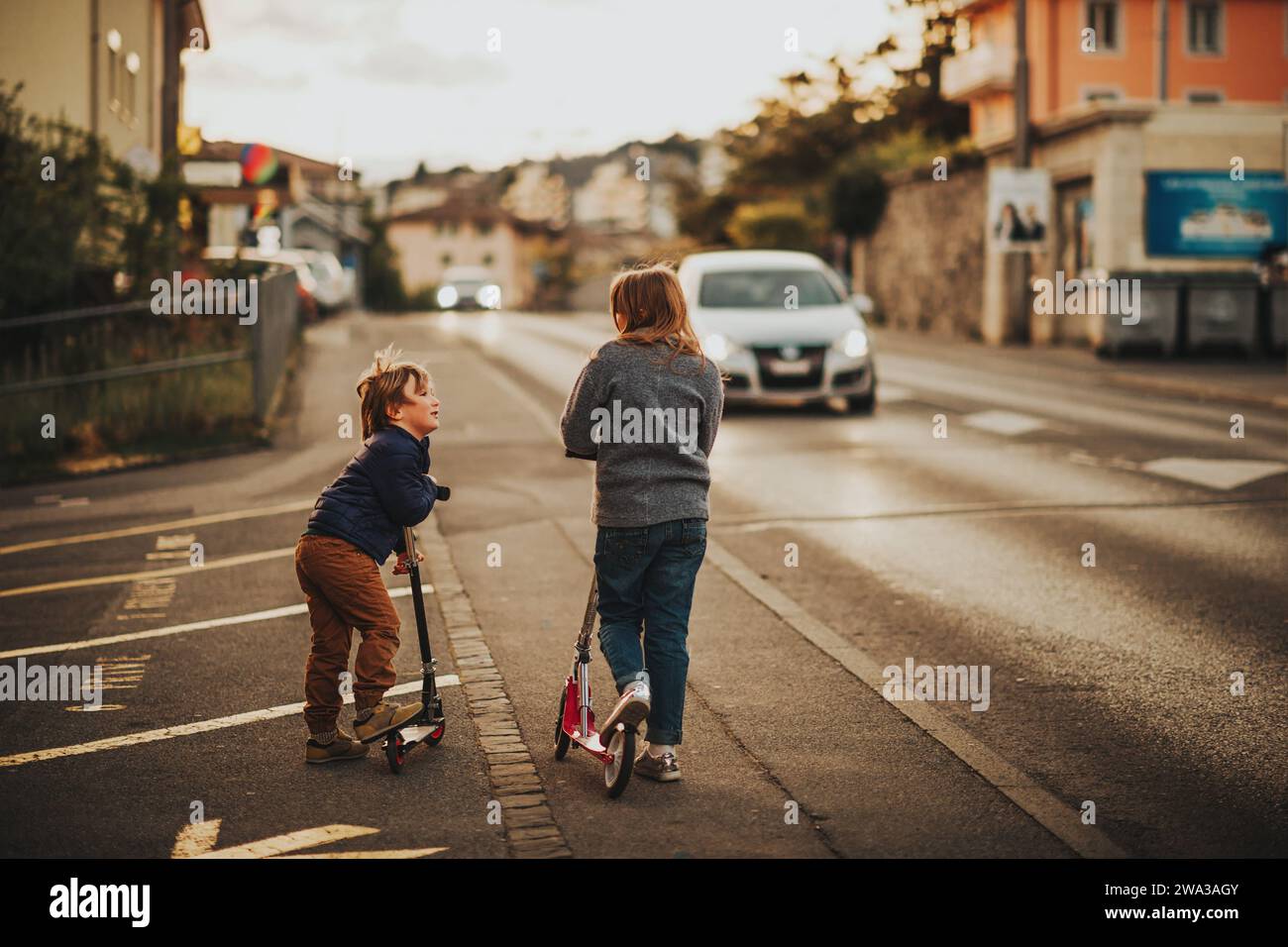 Outdoor portrait of two funny kids riding scooters next to road Stock ...