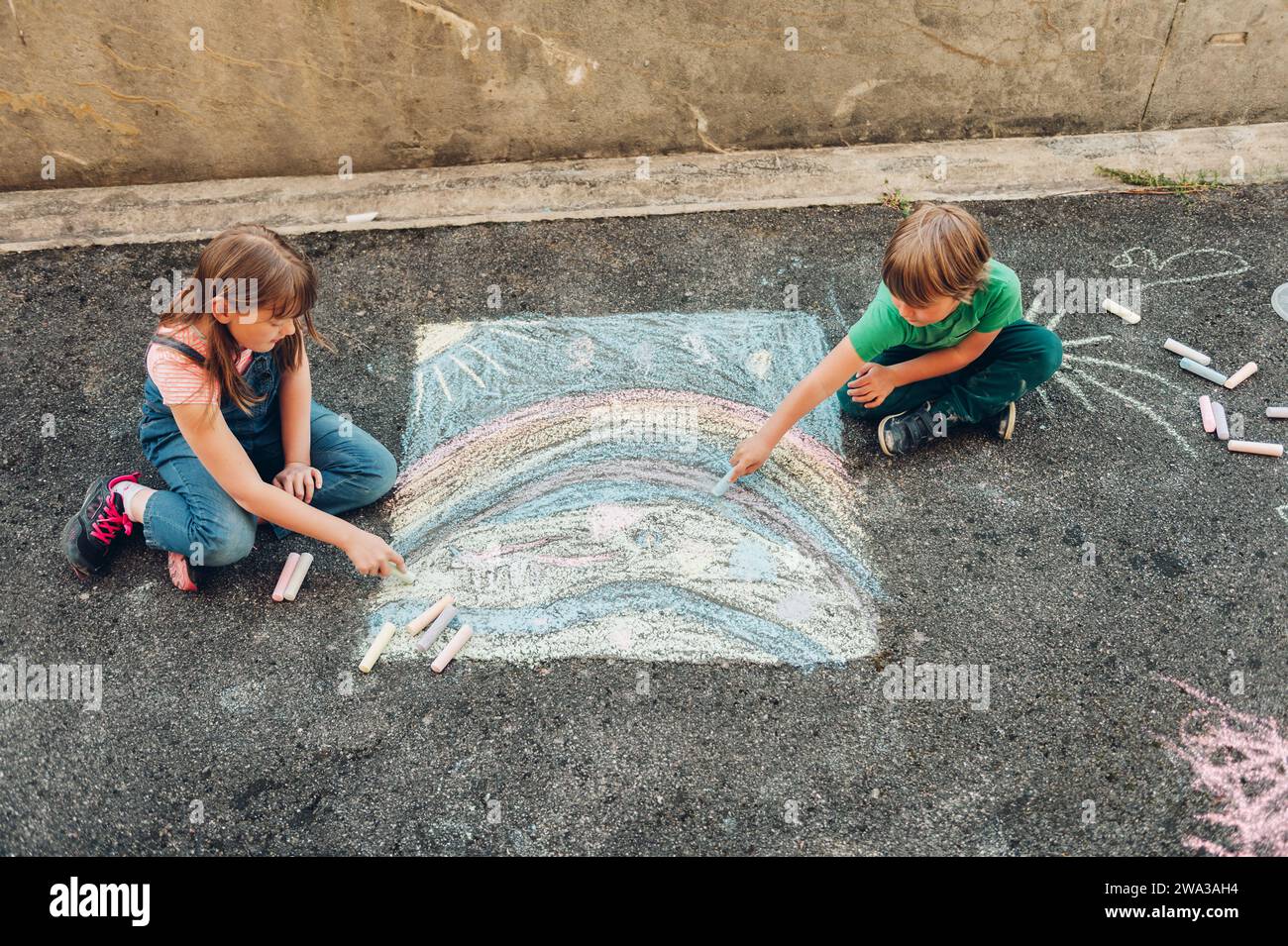 Two funny kids drawing with chalk, children playing together, top view ...