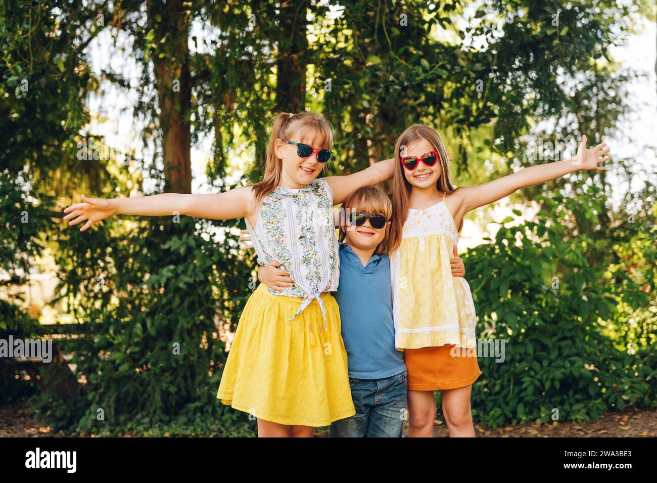 Outdoor portrait of 3 funny kids playing together in summer park. Happy ...