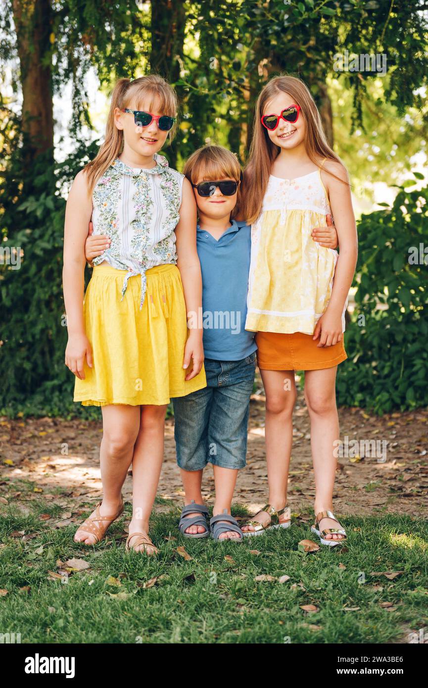 Outdoor portrait of 3 funny kids playing together in summer park. Happy ...