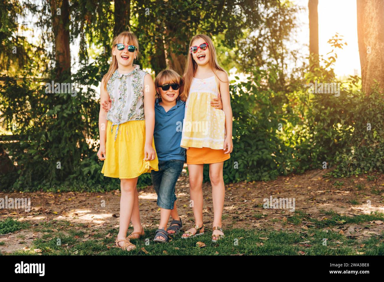 Outdoor portrait of 3 funny kids playing together in summer park. Happy ...