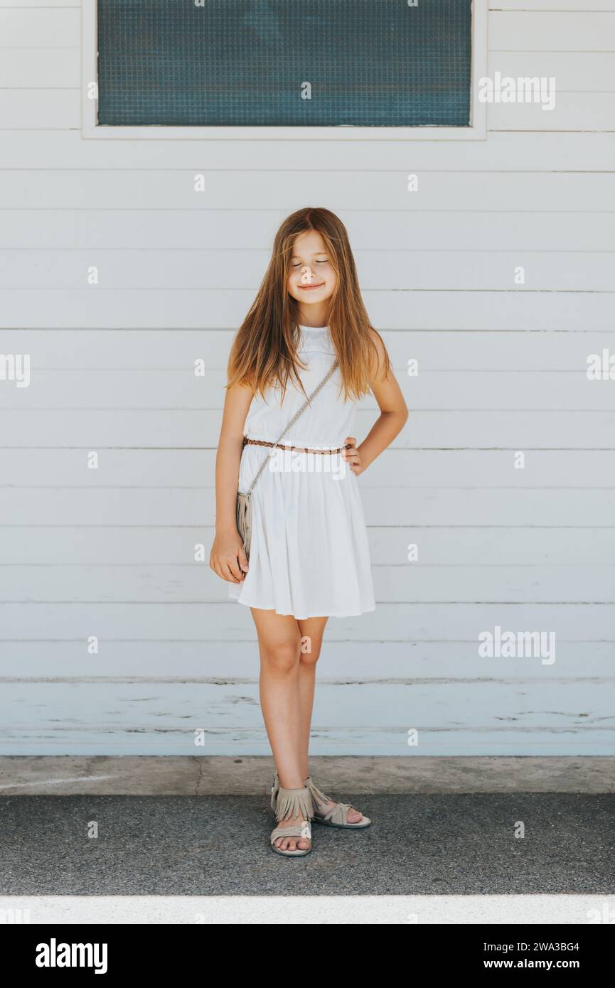 Outdoor portrait of adorable preteen girl wearing white summer dress ...