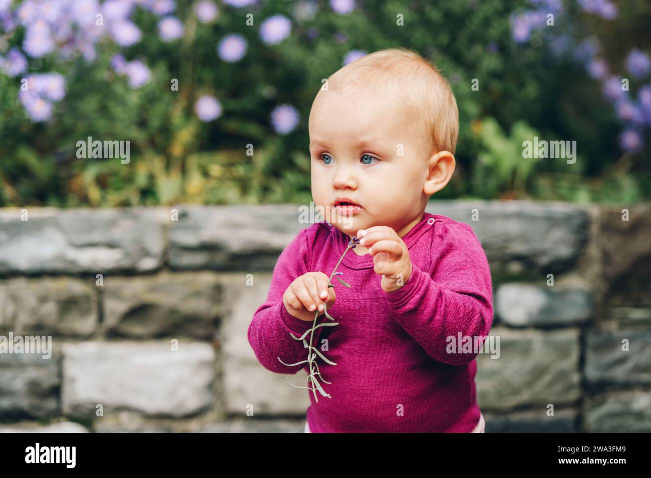 Outdoor portrait of adorable 9-12 month old baby girl playing with ...