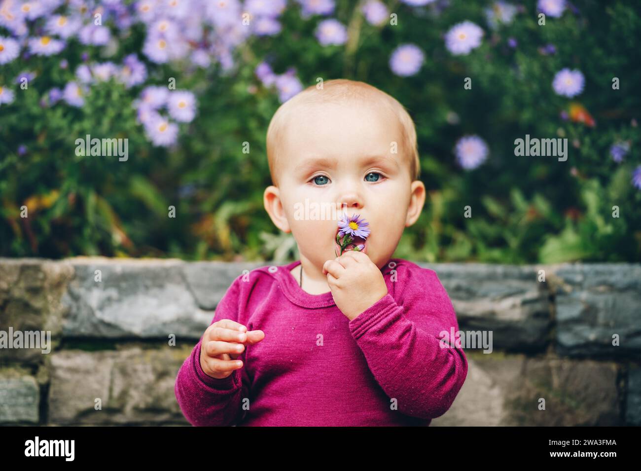 Outdoor portrait of adorable 9-12 month old baby girl playing with ...