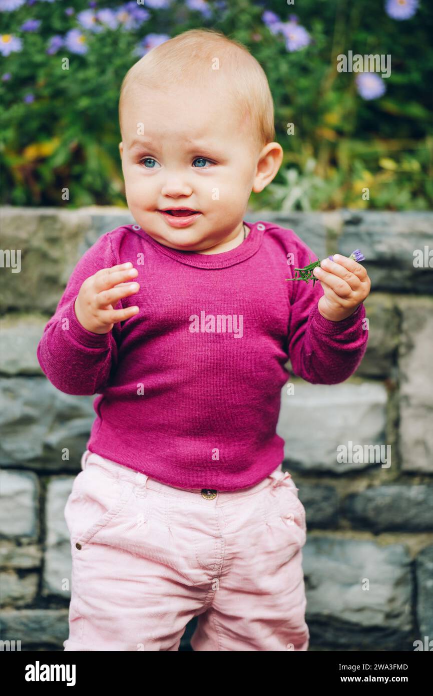 Outdoor portrait of adorable 9-12 month old baby girl playing with ...