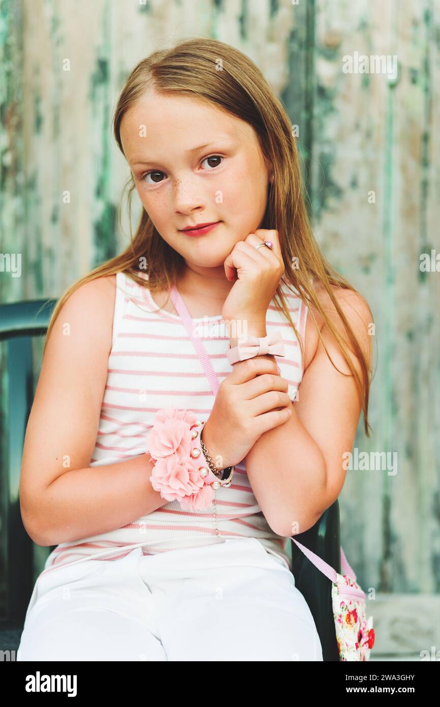 Portrait of a cute little 7-8 year old girl wearing many accessories ...