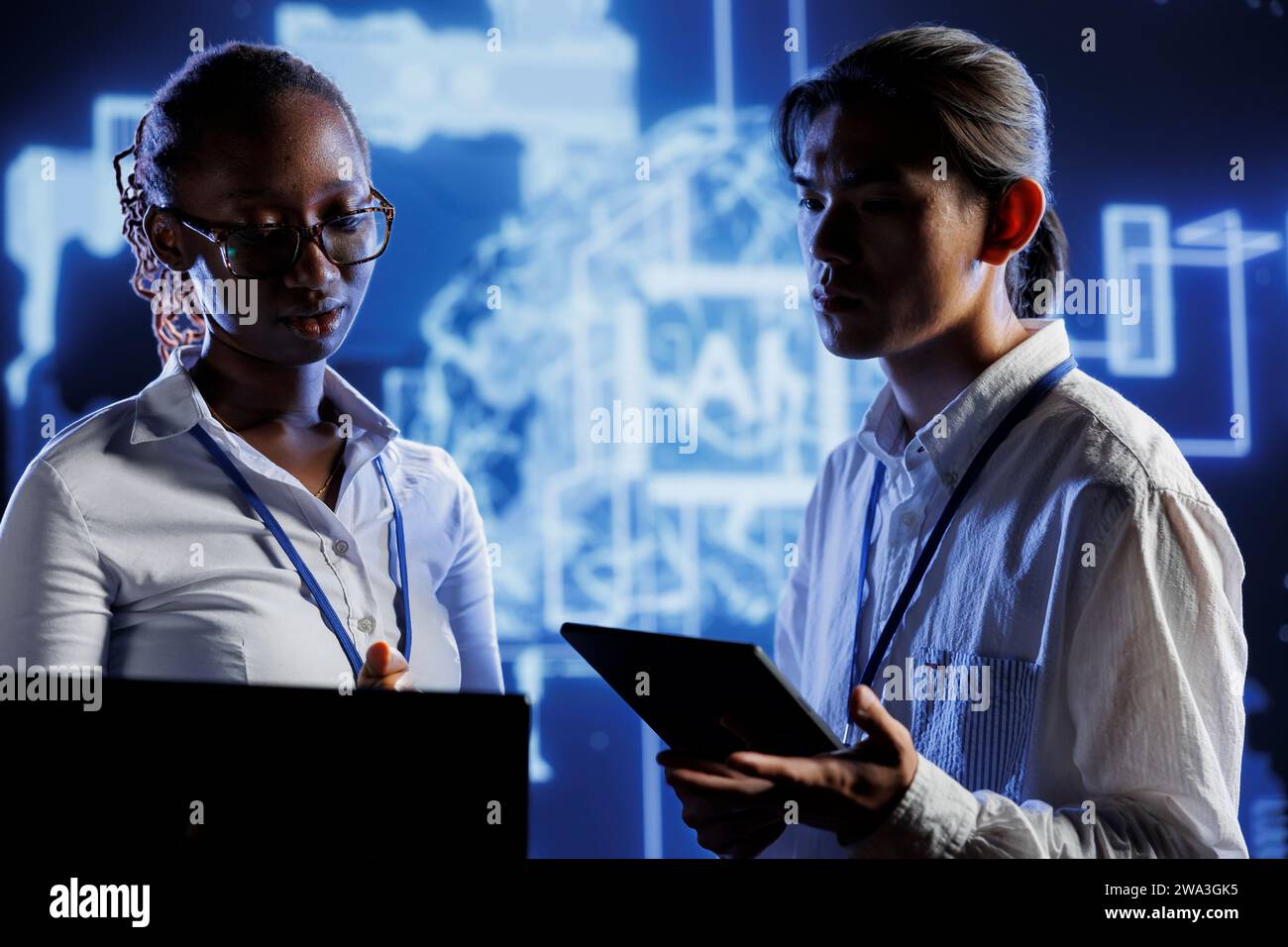 Coworkers using laptop and tablet to maintenance artificial intelligence neural networks ...