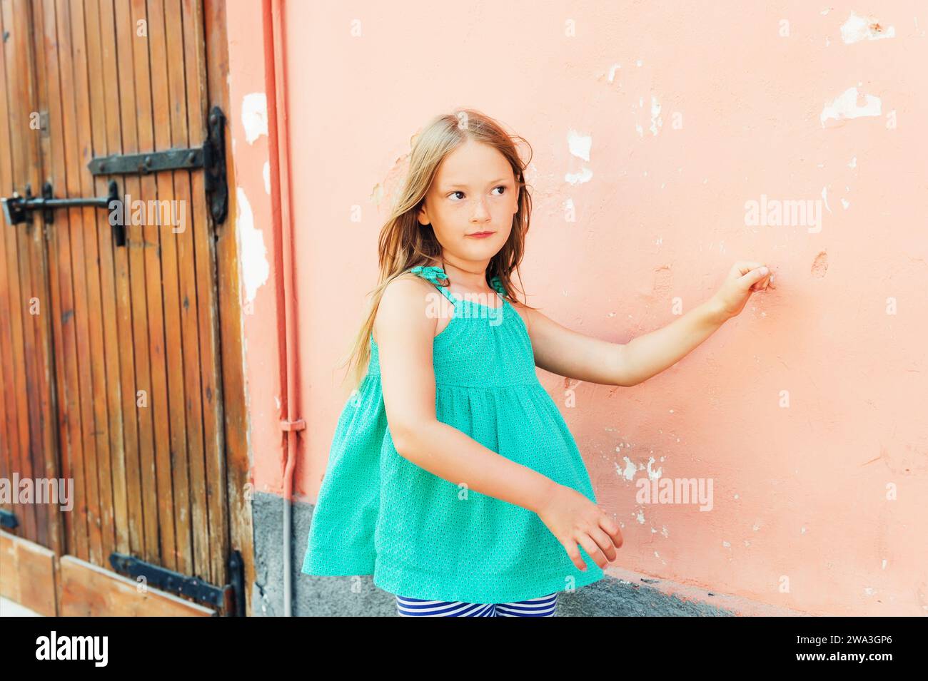 Summer portrait of a cute little girl wearing green top, plying ...