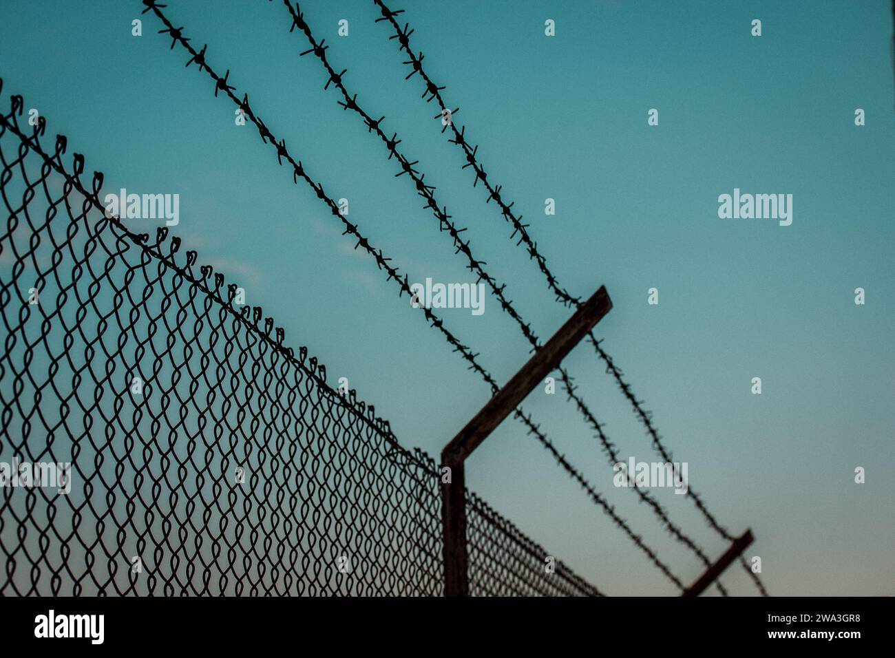 Barbed iron wire against blue sky. Industrial zone protected with a ...