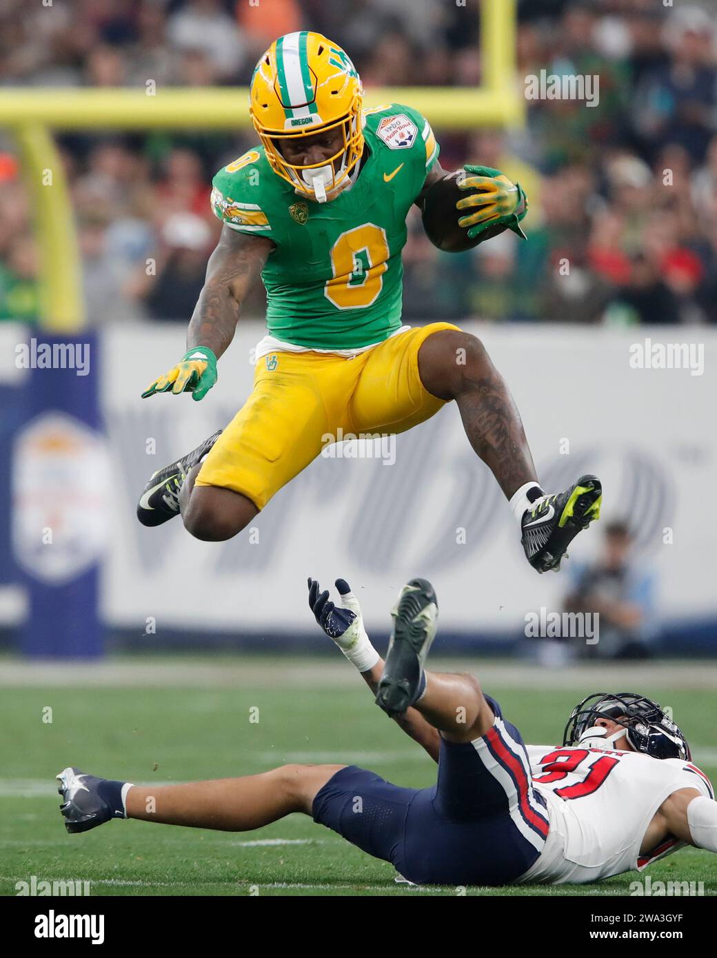 Glendale, Arizona, USA. 1st Jan, 2024. Bucky Irving (0) of the Oregon Ducks leaps over the ...