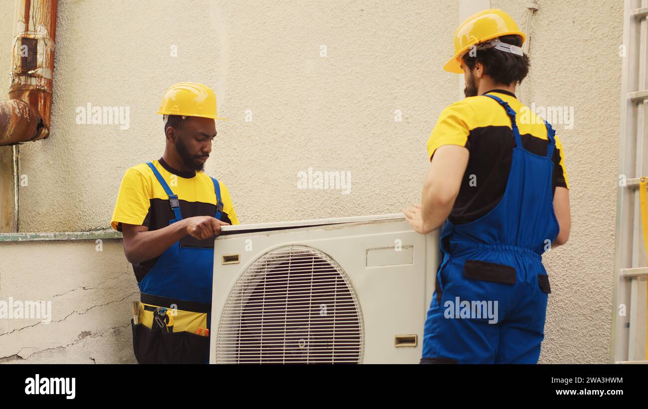 Teamworking licensed servicemen starting work on faulty hvac system ...