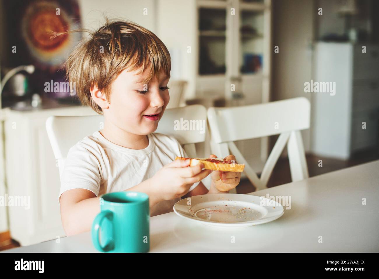 Cute little boy eating his toast with jam and hot chocolate for ...