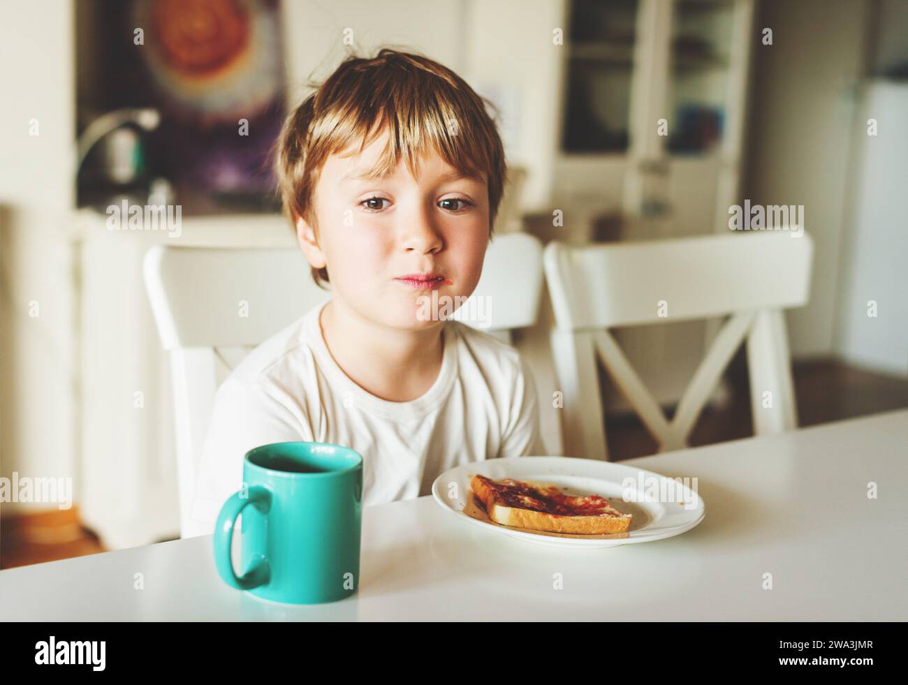 Cute little boy eating his toast with jam and hot chocolate for ...