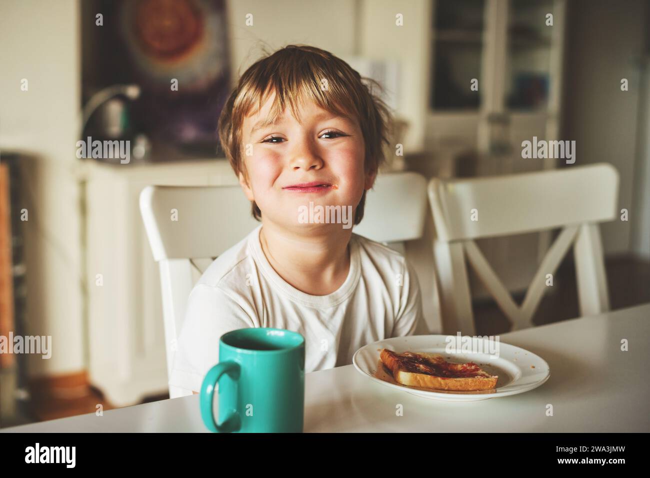 Cute little boy eating his toast with jam and hot chocolate for ...