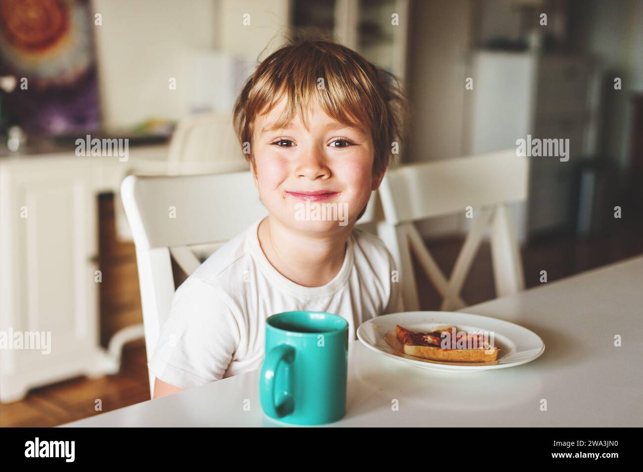 Cute little boy eating his toast with jam and hot chocolate for ...