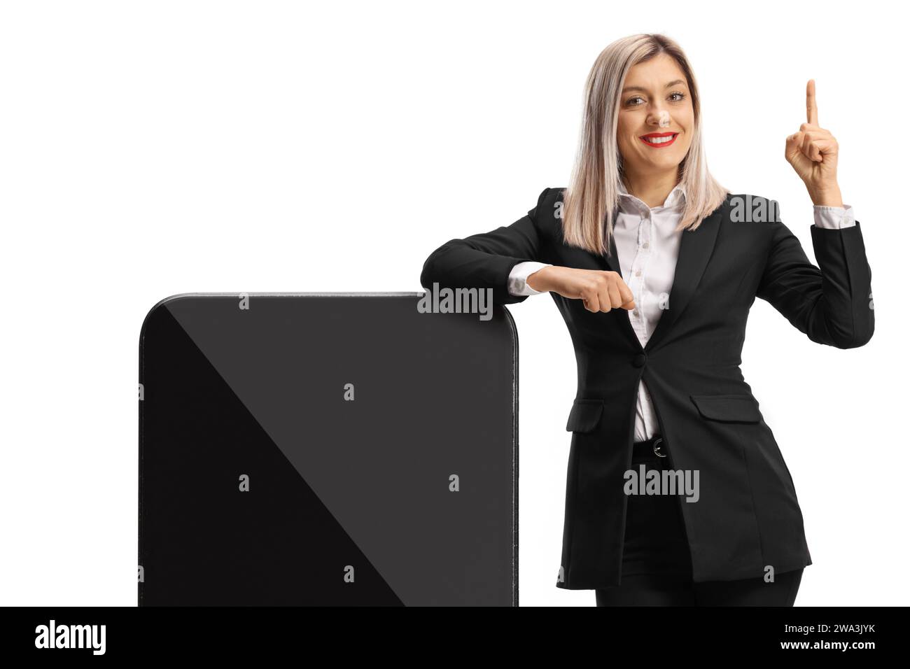 Young professional woman leaning on a black screen and pointing up ...